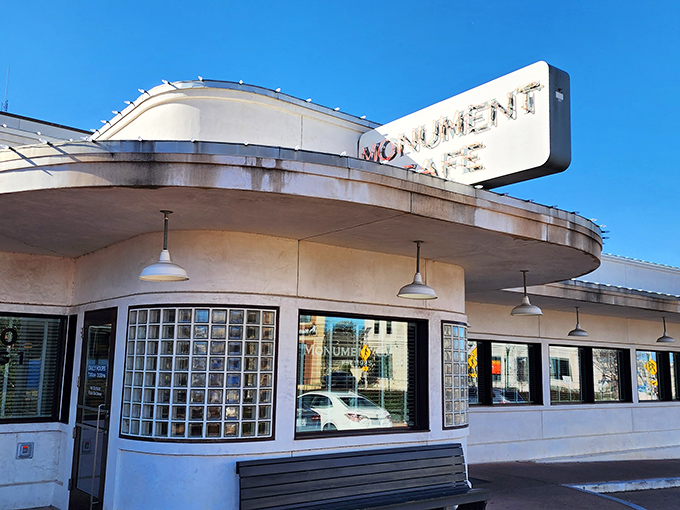 The iconic curved facade of Monument Cafe stands like a mid-century mirage against the Texas sky, promising comfort food paradise within.