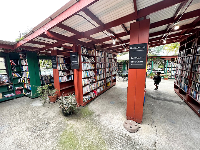 A literary wonderland unfolds beneath corrugated roofing, where black signage guides bibliophiles through this open-air maze of knowledge.