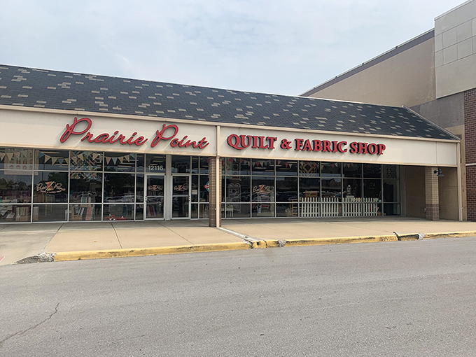 The quilter's equivalent of Willy Wonka's factory beckons with its bright red signage, promising fabric treasures behind those unassuming storefront windows.
