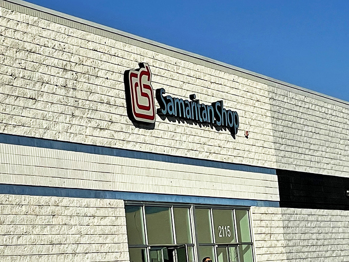 The exterior of Samaritan Shop stretches wide like a treasure chest waiting to be opened, its blue banner promising adventures in second-hand splendor.