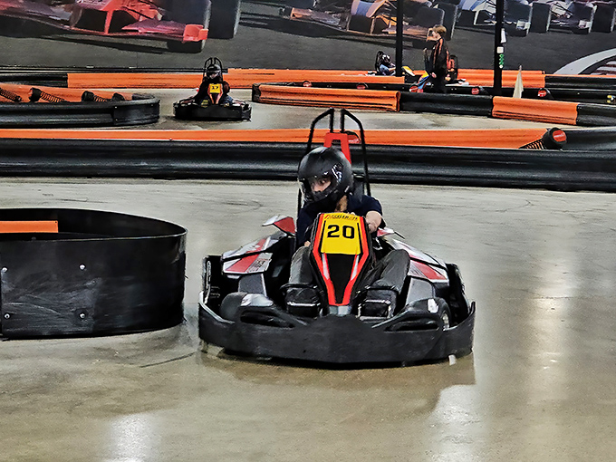 The thrill of the chase! Electric karts zip around tight corners as drivers lean into turns, their focused expressions visible even through helmets.