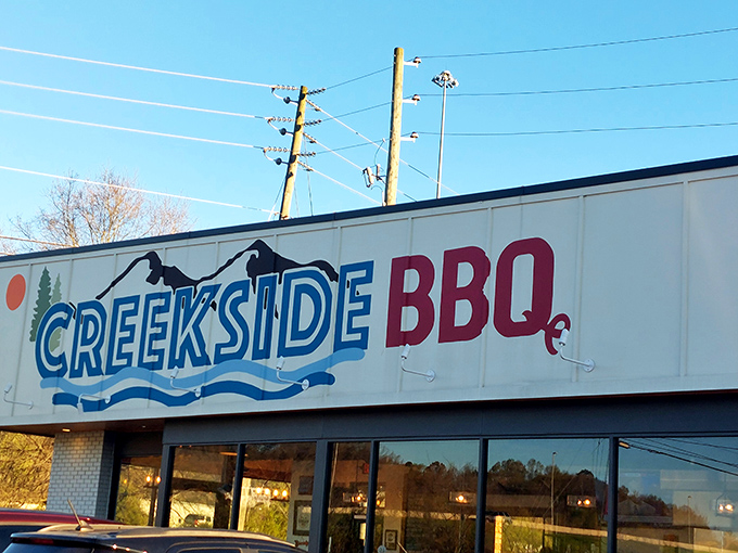 The blue and red Creekside BBQ sign beckons like a lighthouse for the hungry, promising smoky treasures inside this Pelham landmark.