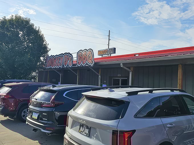 The neon-red sign of Smokey D's BBQ glows like a beacon for hungry souls, promising salvation through smoke and meat in Des Moines.