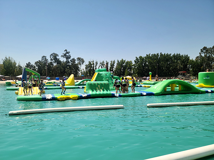 The aquatic playground stretches across crystal-clear water like a neon-colored mirage, promising adventures that'll make your inner child high-five your outer adult.