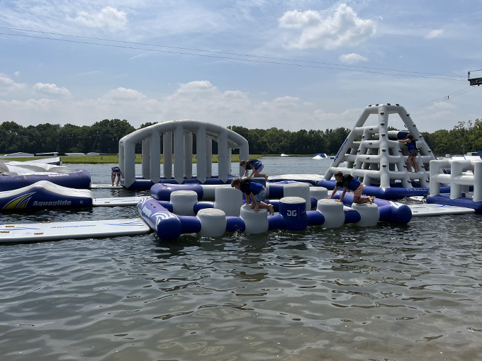 Blue and white inflatable obstacles dot the lake like a playground designed by someone who really understands the joy of controlled chaos.