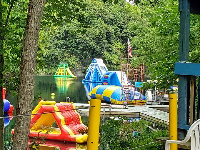 Where the magic happens! Colorful inflatable obstacles float invitingly on crystal-clear quarry waters, promising adventures that'll make your inner child high-five your actual children.