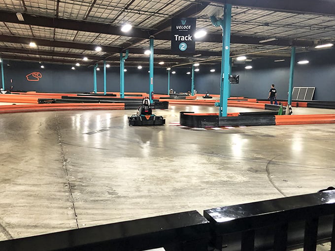 The thrill of the chase! Electric karts zip around tight corners as drivers lean into turns, their focused expressions visible even through helmets.