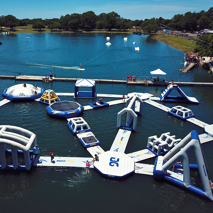 The ultimate adult playground where dignity takes a vacation. White inflatable obstacles float invitingly on blue water, promising equal parts joy and inevitable splashing.