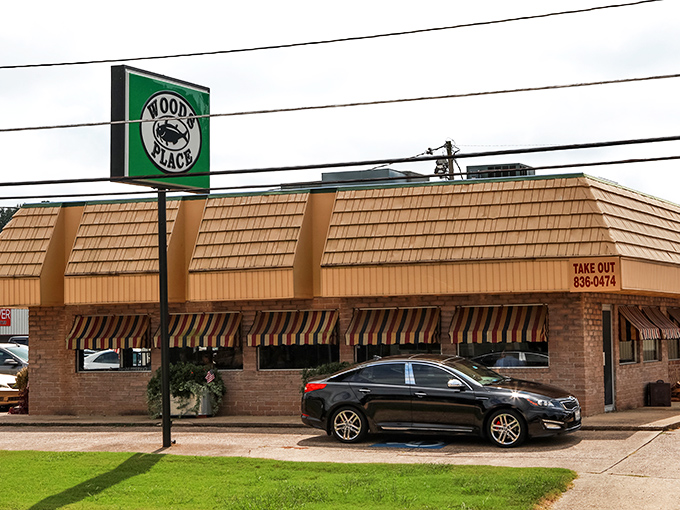The unassuming exterior of Woods Place, with its distinctive green lawn and simple sign, stands as Camden's culinary beacon for catfish aficionados.