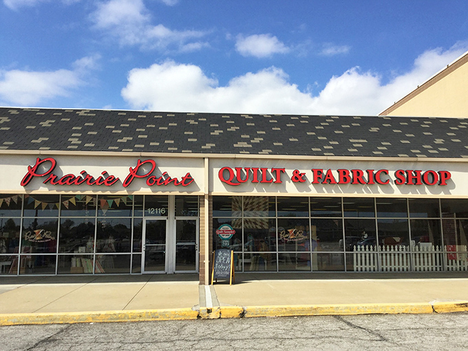 The quilter's equivalent of Willy Wonka's factory beckons with its bright red signage, promising fabric treasures behind those unassuming storefront windows.