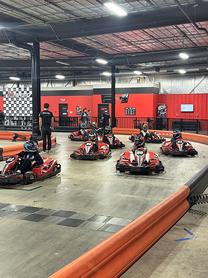 The thrill of the chase! Electric karts zip around tight corners as drivers lean into turns, their focused expressions visible even through helmets.