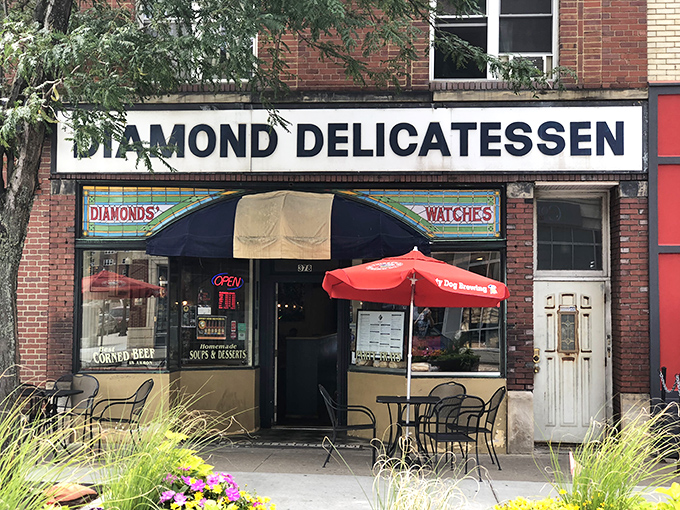 The unassuming storefront of Diamond Deli beckons with its classic brick façade and cheerful red umbrellas—sandwich paradise hiding in plain sight.