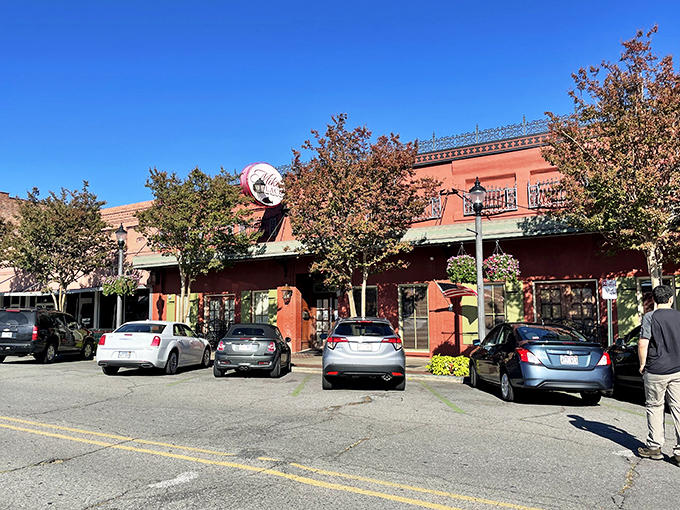 The vibrant red exterior of Mike's Place, framed by blooming crepe myrtles, stands as Conway's culinary beacon for seafood lovers.