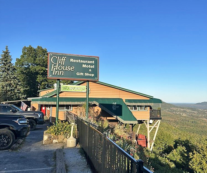 You know that feeling when you take a bite of something so delicious your eyes involuntarily close and you make that little "mmm" sound?
Get ready to make that noise repeatedly at Cliff House Inn in Jasper, Arkansas.
Clinging to the edge of an Ozark Mountain bluff like a determined mountain goat, this unassuming restaurant serves up slices of heaven alongside portions of jaw-dropping scenery that would make a postcard photographer weep with joy.
Arkansas is hiding some serious culinary treasures, and this clifftop wonder might just be the crown jewel&mdash;a place where homestyle cooking meets panoramic views that stretch for 30 miles across the Buffalo River Valley.
The locals have kept this place in their back pocket for years, casually mentioning "that restaurant on the cliff" when visitors ask for recommendations, knowing full well they're about to witness someone's mind being blown in real-time.
Let me walk you through what makes this mountaintop haven worth every twist and turn of the scenic drive to get there, and why the pies alone&mdash;oh those magnificent pies&mdash;justify planning your entire Arkansas vacation around a meal here.
The journey to Cliff House Inn is your first clue that something special awaits.
Arkansas Highway 7 weaves through the Ozarks like a ribbon candy, presenting vistas so beautiful you'll be tempted to pull over every quarter mile for photos.
The route is officially designated as one of America's most scenic byways, which is like being named "one of the prettiest people in Hollywood"&mdash;the competition is fierce.
Just when you think the drive itself is reward enough, you round a bend and spot a modest sign indicating Cliff House Inn.
Nothing flashy or pretentious&mdash;just simple letters promising something authentic ahead.
The gravel crunches under your tires as you pull into the parking lot, and you might momentarily wonder if your GPS has led you astray.
The building before you is humble, weathered by decades of mountain sunshine and winter winds.
It doesn't scream "destination restaurant" until you step out of your car and the full panorama hits you like a visual thunderclap.
You're standing at the precipice of what locals call Arkansas's Grand Canyon.
The Buffalo River Valley stretches before you in a tapestry of endless green, with layers of mountains fading to blue in the distance.
It's the kind of view that makes your problems seem comically small and insignificant&mdash;nature's own version of perspective therapy.
Take a moment here. Breathe. Let your eyes try to process the immensity of the landscape.
This view alone would justify the drive, but incredibly, it's just the appetizer.
Stepping inside Cliff House Inn feels like entering a cherished family cabin that happens to serve incredible food.
The interior is classic Ozark mountain style&mdash;all warm wood paneling, sturdy furniture, and zero pretension.
The walls serve as an informal museum of regional history, covered with framed photographs, vintage signs, music memorabilia, and enough local artifacts to tell the story of this corner of Arkansas without saying a word.
Ceiling fans spin lazily overhead, circulating the intoxicating aromas drifting from the kitchen&mdash;butter, sugar, baking pastry, sizzling meats, and that indefinable scent of "someone who really knows what they're doing is cooking."
The main dining room features a wall of windows facing the canyon, ensuring that nearly every table comes with a million-dollar view.
You'll spot families lingering over dessert, couples leaning toward each other in conversation, solo travelers with books or maps spread before them, and groups of motorcyclists taking a scenic break from the winding roads.
The clientele is as diverse as the landscape&mdash;this is a place that appeals to everyone from luxury travelers to budget road-trippers, united by their appreciation for authentic experiences and good food.
The atmosphere buzzes with convivial energy&mdash;the satisfied murmur of conversation, punctuated by occasional gasps from first-timers as they notice a red-tailed hawk soaring at eye level outside the windows.
There's no background music needed here; the soundtrack is purely human, with occasional laughter rising above the gentle clinking of silverware against plates.
The staff moves with the unhurried confidence of people who know they're part of something special.
They greet regulars by name and welcome newcomers with the genuine warmth that defines Ozark hospitality.
No corporate-trained personas here&mdash;just authentic friendliness and the quiet pride of people who know they work at a beloved institution.
When the menu arrives at your table, you might be surprised by its breadth.
This isn't some precious farm-to-table concept with five artfully described options&mdash;it's a comprehensive celebration of hearty American classics and regional specialties designed to satisfy every appetite.
Breakfast is served all day, because the kitchen understands that sometimes you need fluffy pancakes and crispy bacon at 4 PM.
For lunch and dinner, you'll find everything from hand-battered fried catfish to substantial steaks cooked precisely to your preference.
The Arkansas Catfish Platter pays homage to local traditions with cornmeal-crusted fillets that remain delicately flaky inside their golden exterior.
It comes with all the proper accompaniments&mdash;creamy coleslaw, pinto beans, and french fries that achieve that perfect balance between crispy and tender.
The chicken fried steak is another standout&mdash;a tender beef cutlet hammered thin, breaded, fried to golden perfection, and smothered in peppered cream gravy that should be studied by culinary students as a masterclass in Southern sauce-making.
For those seeking something from the waters, the seafood options might seem surprising for a mountain restaurant, but the blackened sea bass and shrimp dishes have converted many skeptics.
The house specialties include the "Cliff House Steak"&mdash;a USDA prime aged ribeye served with cajun butter that caramelizes slightly on the hot beef, creating a flavor profile that's both sophisticated and utterly comforting.
Vegetarians aren't treated as an afterthought either, with substantial salads and pasta options that reflect the same commitment to satisfying, flavorful food.
Every dish arrives in portions that reflect the generous spirit of the place&mdash;this is not where you come for tiny artful arrangements surrounded by negative space on oversized plates.
This is honest, abundant food that respects both traditional techniques and your appetite.
But let's be real&mdash;as good as the main courses are, they're merely opening acts for the true headliners.
The pies at Cliff House Inn aren't just desserts; they're edible monuments to what happens when generations of baking wisdom meet quality ingredients and exacting standards.
The dessert menu reads like poetry for those with a sweet tooth, featuring creations that have been perfected over decades of daily production.
The undisputed royalty is the "Company's Comin' Pie"&mdash;officially designated as the Arkansas state pie.
This cloud-like creation features a meringue crust studded with pecans, filled with a heavenly mixture of whipped cream and pineapple.
It's simultaneously rich and light, sweet but not cloying, familiar yet unlike anything you've tasted before.
The possum pie (relax, it's just a name) is another signature&mdash;a layered masterpiece with a cream cheese bottom, chocolate custard middle, and whipped topping, all nestled in a pecan shortbread crust.
Each bite delivers multiple textures and flavors that somehow harmonize perfectly, like a well-rehearsed choir hitting that perfect chord.
For chocolate enthusiasts, the Fudge Bourbon Pecan Pie delivers a grown-up riff on a Southern classic, with just enough bourbon to add complexity without overwhelming the deep chocolate notes.
Fruit pie lovers will find seasonal offerings that showcase the bounty of Arkansas orchards&mdash;fresh peach in summer, apple in fall, and berry varieties when they're at peak sweetness.
Each slice arrives looking like it was transported directly from a baking competition photoshoot&mdash;golden crusts, perfectly set fillings, and precisely the right amount of accompanying whipped cream or ice cream.
No wonder many regulars have been known to order dessert first, citing life's uncertainty as perfectly reasonable justification.
What makes these pies extraordinary isn't some secret ingredient or cutting-edge technique&mdash;it's the opposite.
They represent the perfection of simplicity, the result of doing basic things exceptionally well, over and over again.
Real butter, fresh ingredients, hands that know exactly how long to work the dough, and an understanding that some things simply cannot be rushed.
In a world increasingly dominated by automation and shortcuts, these pies stand as delicious rebellion&mdash;proof that the old ways sometimes remain unsurpassed.
One of the most charming aspects of Cliff House Inn is how it transforms with the seasons, giving you a perfect excuse to return throughout the year.
Spring brings an explosion of dogwood and redbud blossoms that dot the valley below with bursts of white and pink against the fresh green backdrop.
The air feels charged with renewal, and the dining room hums with the energy of winter-weary patrons celebrating the return of warmer days.
Summer bathes the landscape in deep emerald tones, occasionally interrupted by dramatic thunderstorms that you can watch roll through the valley from your protected perch.
There's something primal and thrilling about enjoying your blackberry cobbler while lightning illuminates the distant ridges.
Fall is the season of pilgrimage, when the valley becomes a kaleidoscope of crimson, amber, and gold.
The restaurant fills with leaf-peepers from across the country, cameras at the ready, all united in their appreciation of nature's most spectacular color show.
Even winter has its austere charms, when bare trees reveal the sculptural topography of the landscape and occasional snow transforms the view into a monochromatic masterpiece.
On clear winter days, visibility stretches farther than any other season, revealing distant features normally obscured by summer haze.
The menu subtly shifts with these seasonal changes&mdash;more hearty comfort foods in colder months, lighter fare showcasing fresh produce during growing season.
The pie selection especially reflects this rhythm, featuring whatever fruits are at their peak of flavor.
While many visitors come just for a meal, Cliff House Inn offers more than just culinary delights.
True to its name, there are simple but comfortable motel-style accommodations for those wise enough to want to linger.
Imagine waking up to sunrise over the Buffalo River Valley, mist rising from the forests below as the world gradually illuminates in soft pastels.
It's the kind of morning view that recalibrates your entire perspective on what constitutes a good start to the day.
A small gift shop offers locally made crafts, jams, and souvenirs that let you take a piece of the Ozarks home.
Yes, it's touristy in the most charming way&mdash;the kind of place where you might find a handcrafted wooden ornament that becomes a treasured reminder of your visit.
For the adventurous, the restaurant serves as an ideal base camp for exploring the surrounding natural wonders.
The staff gladly shares insider tips about nearby hiking trails, swimming holes, and scenic spots that don't make it into the tourist guides.
Some of Arkansas's most spectacular natural features are within easy reach&mdash;the Buffalo National River, Lost Valley, Steel Creek, and the quaint town of Jasper itself.
What ultimately elevates Cliff House Inn from merely good to genuinely special is the intersection of food, location, and people.
The staff embodies that particular brand of Ozark hospitality that feels both respectful and familial at once.
They understand they're not just serving food&mdash;they're creating memories that visitors will carry with them long after the last bite of pie is gone.
The other diners contribute to this atmosphere too.
At adjoining tables, you might find Harley-Davidson enthusiasts comparing notes on mountain roads, multi-generational families celebrating milestones, or solo travelers finding unexpected conversation with strangers who soon feel like friends.
In an era when authentic experiences feel increasingly rare, Cliff House Inn offers something genuine&mdash;a place untouched by the homogenizing forces of modern chain restaurants and corporate hospitality.
It simply excels at being exactly what it is&mdash;a slice of Ozark culture served with spectacular views and unforgettable pie.
For more information about their current hours, seasonal specialties, or to book a room for an overnight stay, visit the Cliff House Inn's website or Facebook page.
Use this map to find your way to this mountaintop culinary treasure, but drive carefully&mdash;the views are distracting and the roads demand attention.
Some treasures are worth the journey, especially when they come with a slice of pie that might just change your life.