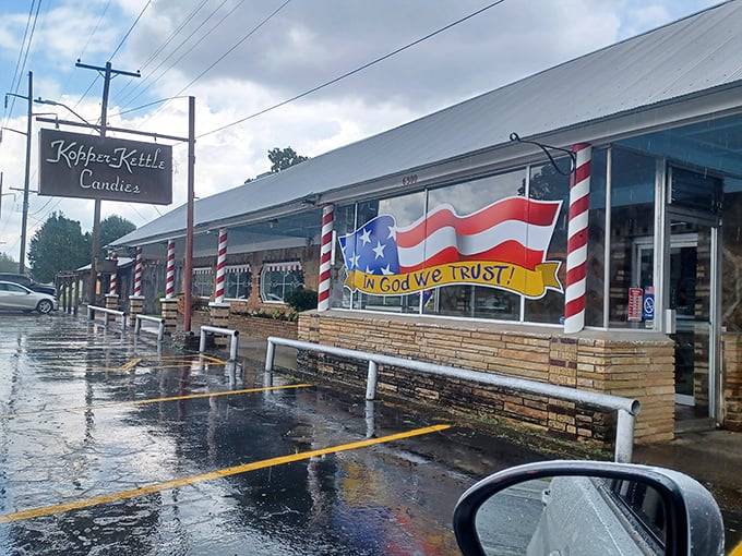 The iconic storefront of Kopper Kettle Candies stands resilient against Arkansas rain, its candy-striped poles promising sweet refuge from ordinary life.