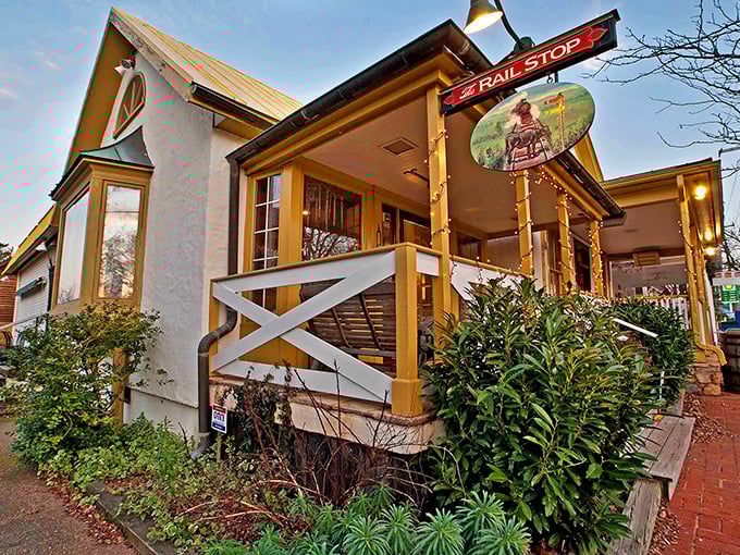 The charming yellow exterior of The Rail Stop beckons like an old friend, promising comfort and culinary delights beneath that distinctive red sign.