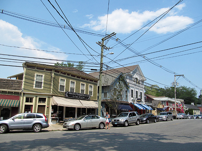 Quaint historic buildings and a peaceful atmosphere await you while exploring this charming village street lined with cars and shops.