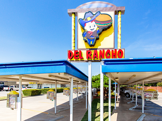 The classic drive-in canopy stands like a time portal to 1956, promising comfort food treasures beneath its nostalgic blue trim. 