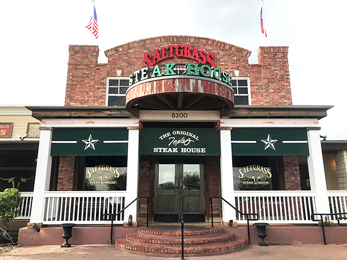 The brick facade of Saltgrass stands like a carnivore's lighthouse, beckoning hungry travelers with its iconic red and green signage against the Oklahoma sky.