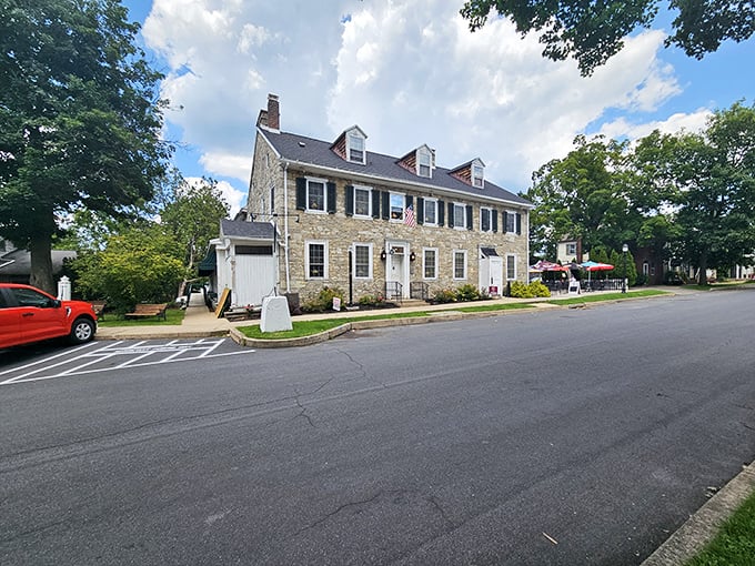 The historic limestone exterior of Duffy's Tavern stands proudly in Boalsburg, with colorful umbrellas inviting you to enjoy Pennsylvania sunshine while dining al fresco.