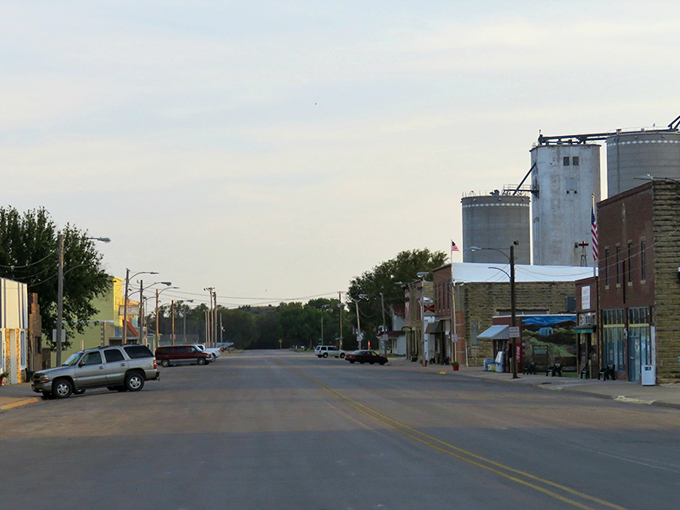 Main Street Lucas stretches toward the horizon, where grain elevators stand like prairie sentinels against the Kansas sky. Small-town America at its most authentic.