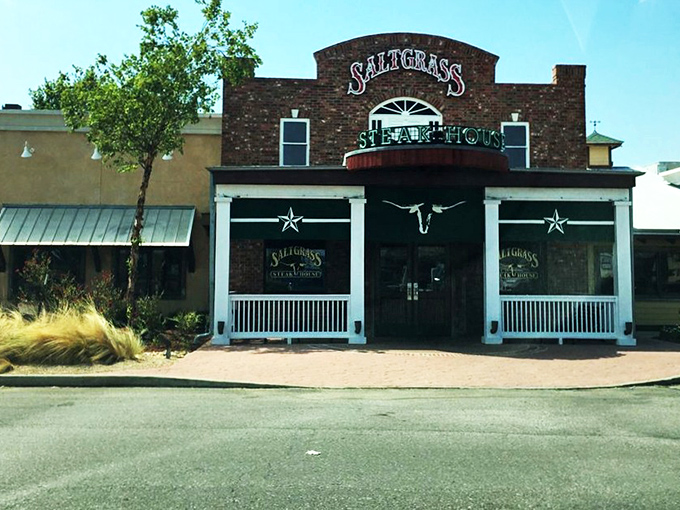 The brick facade of Saltgrass stands like a carnivore's lighthouse, beckoning hungry travelers with its iconic red and green signage against the Oklahoma sky.