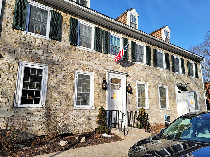 The historic limestone exterior of Duffy's Tavern stands proudly in Boalsburg, with colorful umbrellas inviting you to enjoy Pennsylvania sunshine while dining al fresco.