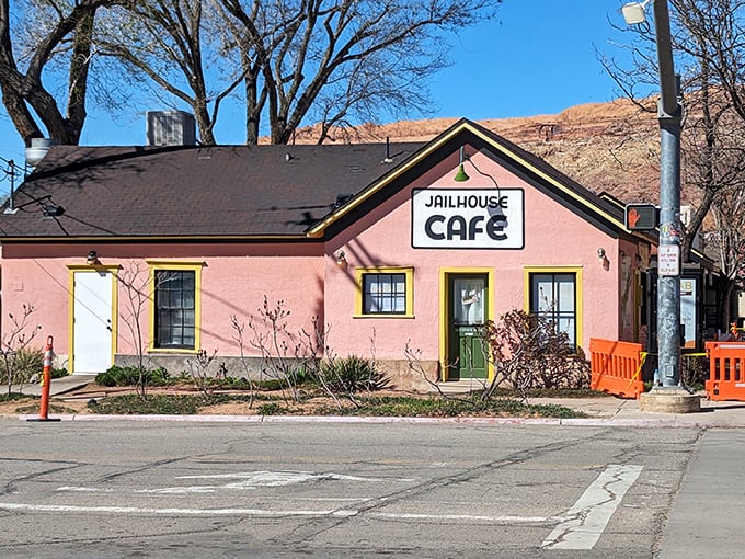 The salmon-pink jailhouse turned breakfast haven stands like a cheerful rebellion against ordinary dining, its yellow door beckoning hungry travelers into delicious captivity.