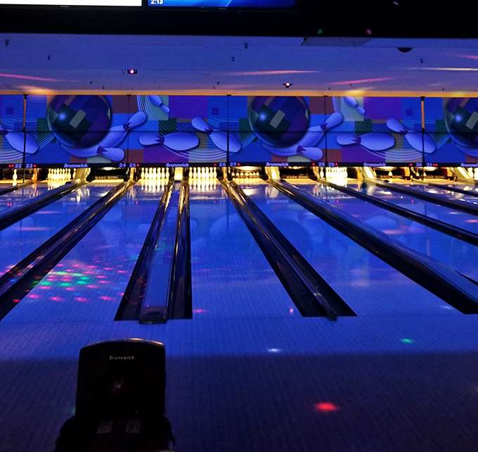 Under cosmic bowling lights, the lanes transform into a neon wonderland where even gutter balls look spectacular in purple haze.