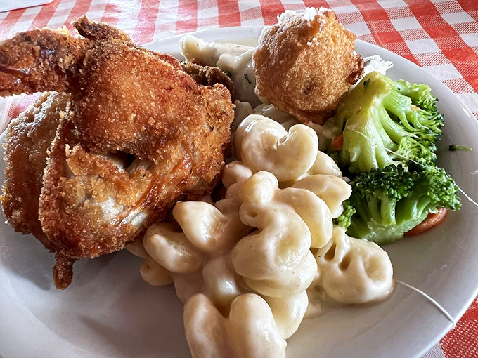 Mac and cheese that doesn't come from a box, served alongside perfectly fried chicken and fresh vegetables. This plate understands the importance of balance in comfort food.