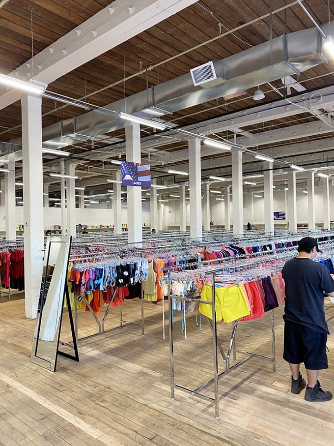 Even the ceiling tells a story in this cavernous space where American flags hang proudly above racks of clothing awaiting their next chapter.