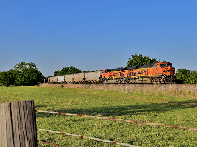 A BNSF freight train cuts through Perry's pastoral landscape, a steel reminder of the railways that once determined where towns would rise or fall.