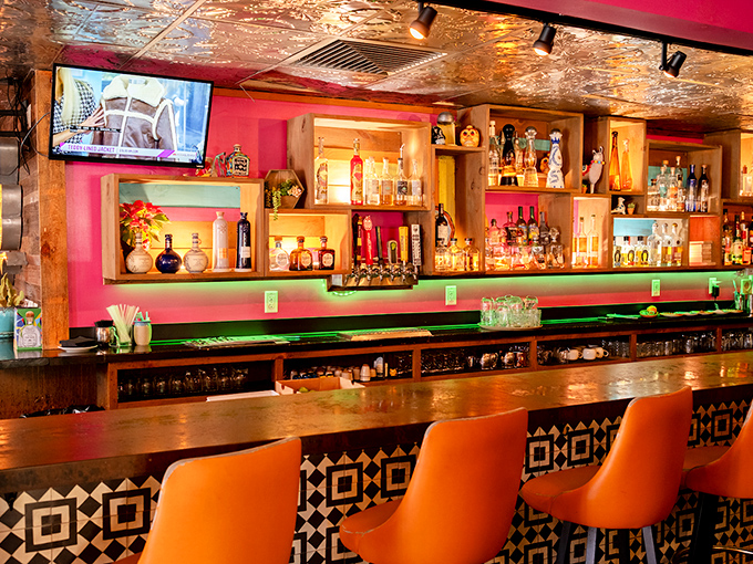 A bar that doesn't whisper "tequila"—it sings it with hot pink walls, amber lighting, and enough bottles to make decision-making delightfully difficult.