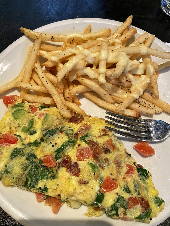 An omelet that's having an identity crisis as a California BLT, paired with fries that are clearly overachievers. Comfort food with a college degree.