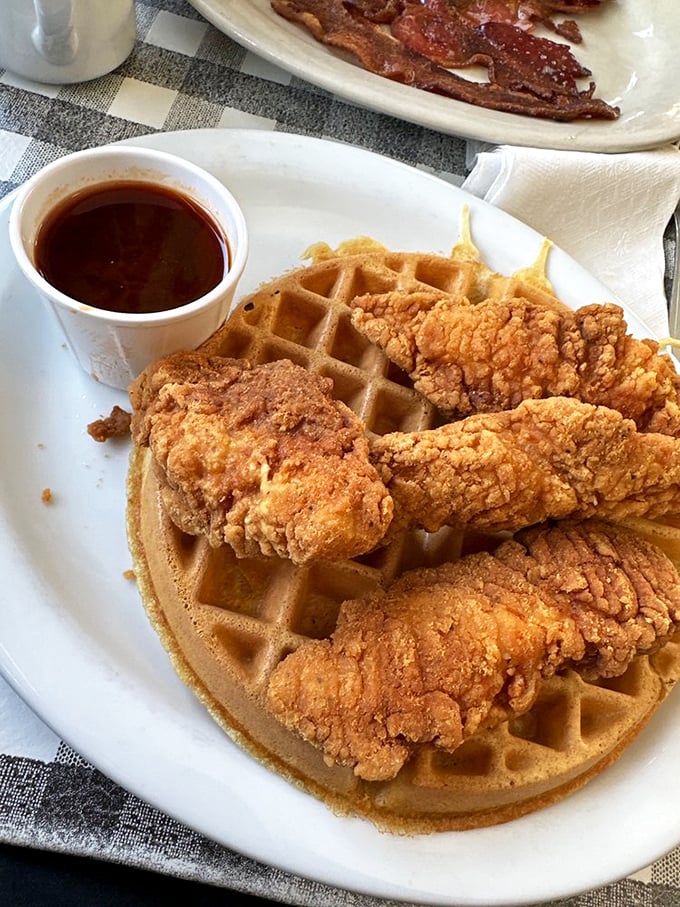 Chicken and waffles: where Southern comfort meets breakfast rebellion, all waiting to be baptized in that little cup of maple syrup.