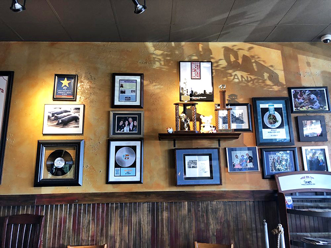The wall of fame tells stories of competition victories, while the orange booths below await the next generation of barbecue believers.