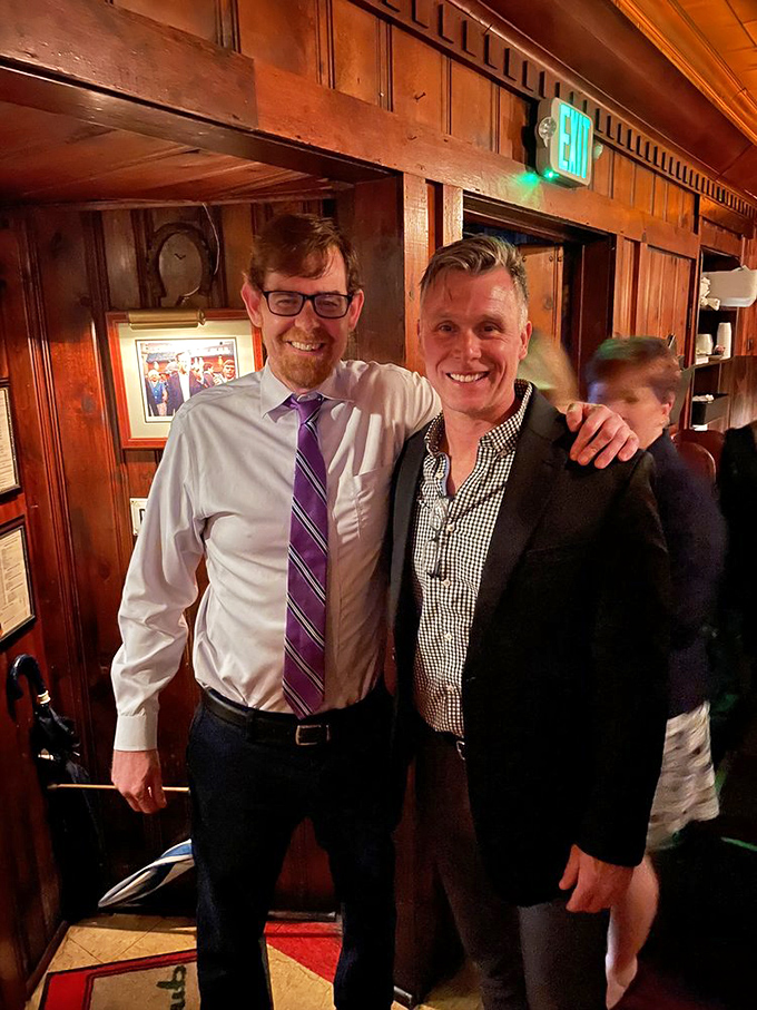 Two patrons sharing a moment in the warm glow of The Pine Club. Some friendships are best celebrated over exceptional food.