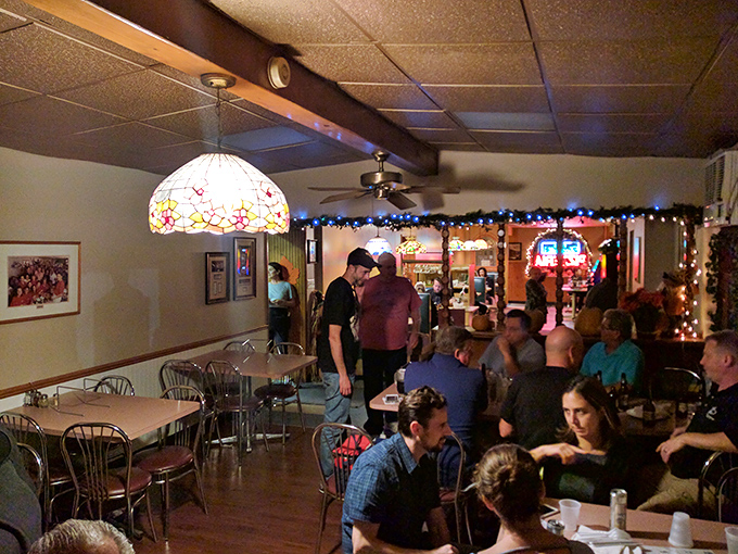 Stained glass lamps cast a warm glow over diners engaged in the sacred ritual of pizza appreciation. Notice the absence of phones&mdash;the pie demands attention. 