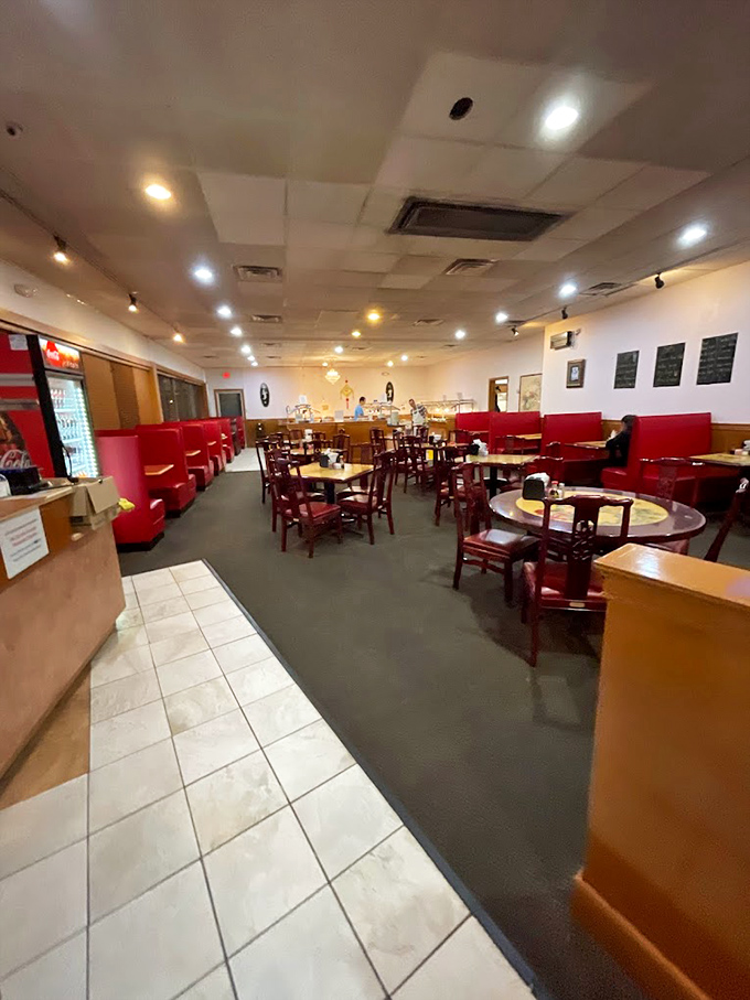 The dining room waits in peaceful anticipation, each red booth a private island where food becomes the main conversation topic.