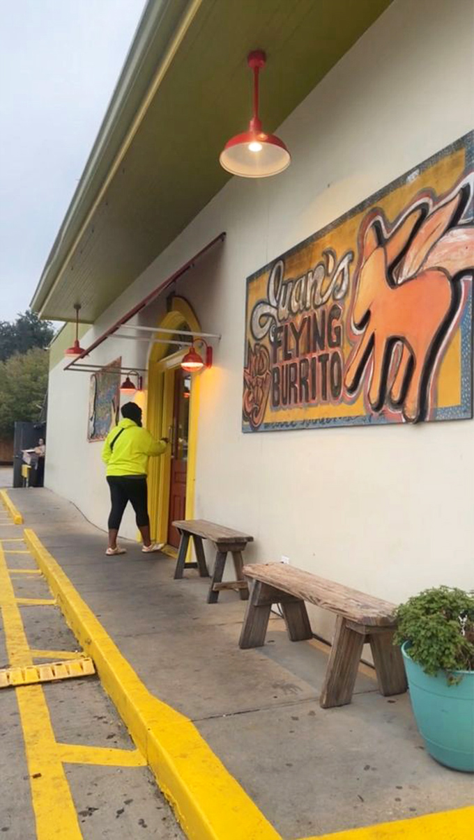 The yellow door says "come in" while the wooden benches say "stay awhile." A storefront that promises adventure without pretension.
