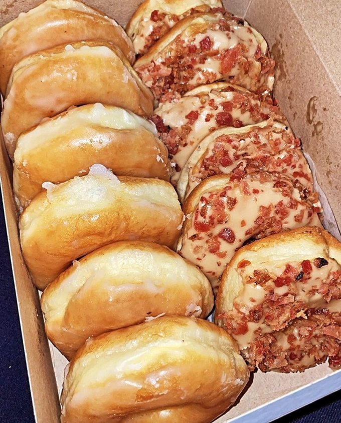 The holy donut alliance: classic glazed sitting beside maple bacon beauties&mdash;proof that both tradition and innovation deserve equal billing in the pantheon of breakfast perfection.