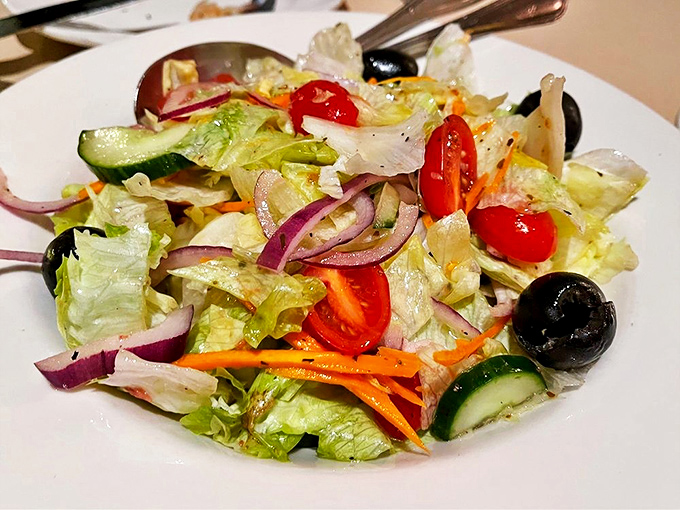 A house salad that actually deserves respect. Crisp vegetables, punchy olives, and that vinaigrette&mdash;proof that simple ingredients handled properly create magic.