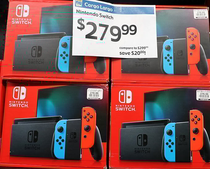 Nintendo Switch consoles stacked like high-tech bricks building a pathway to gaming joy with a $20 discount sweetening the deal.