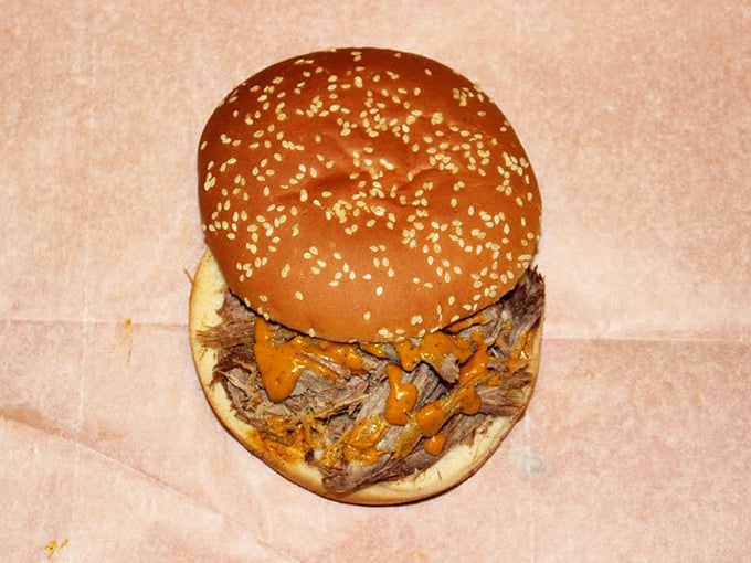 This isn't just a sandwich&mdash;it's an architectural marvel of smoke-kissed meat and sauce, balanced precariously on a humble sesame bun.