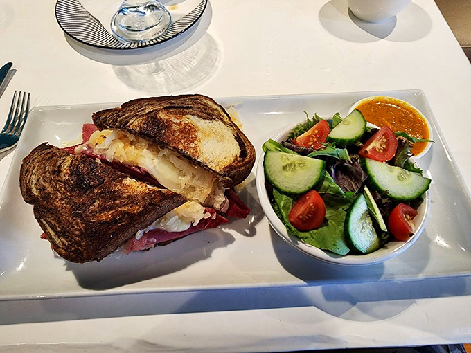 A Reuben sandwich that's dressed better than most people at a wedding, accompanied by a salad that actually deserves to be eaten.
