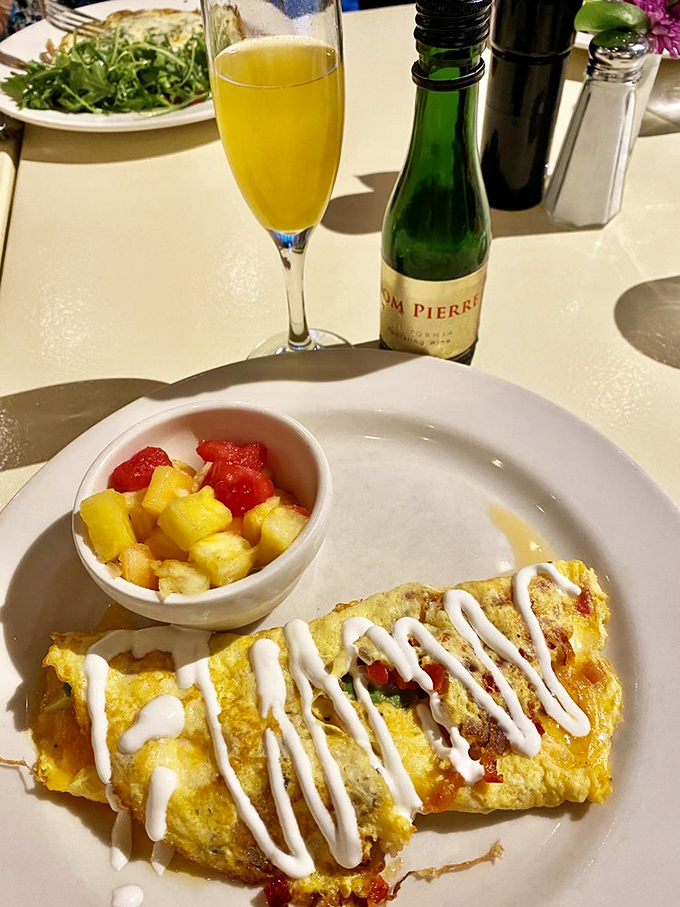 Brunch perfection: a colorful omelet alongside fresh fruit and a sunshine-yellow Bellini. The breakfast of champions who don't have to operate heavy machinery afterward.