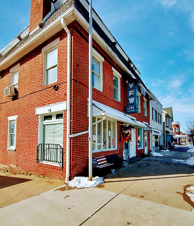 This crimson-bricked corner shop with its patriotic bench invites passersby into a slice of small-town commerce where neighbors still greet each other by name.