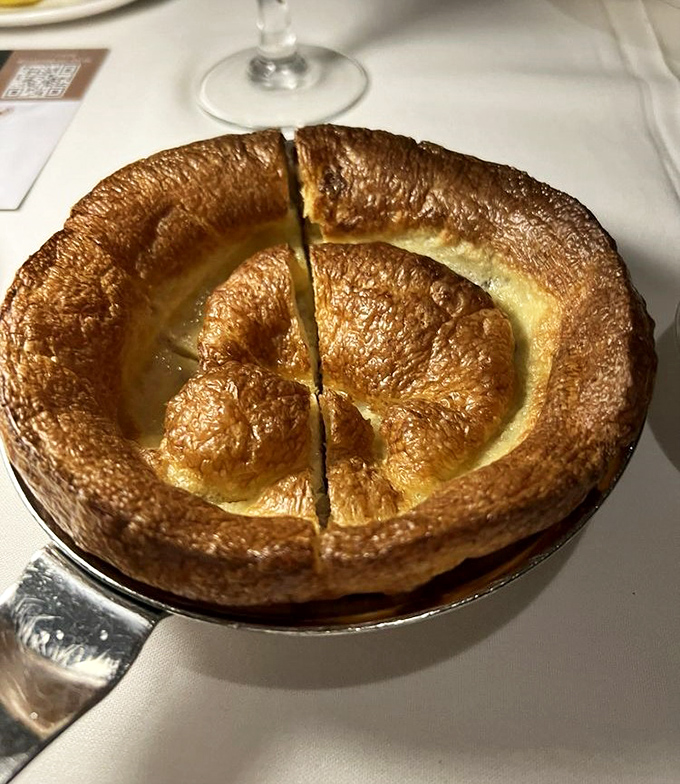 The Yorkshire pudding rises to dramatic heights like a souffle with ambition—crispy exterior, cloud-like inside, ready for its au jus bath.