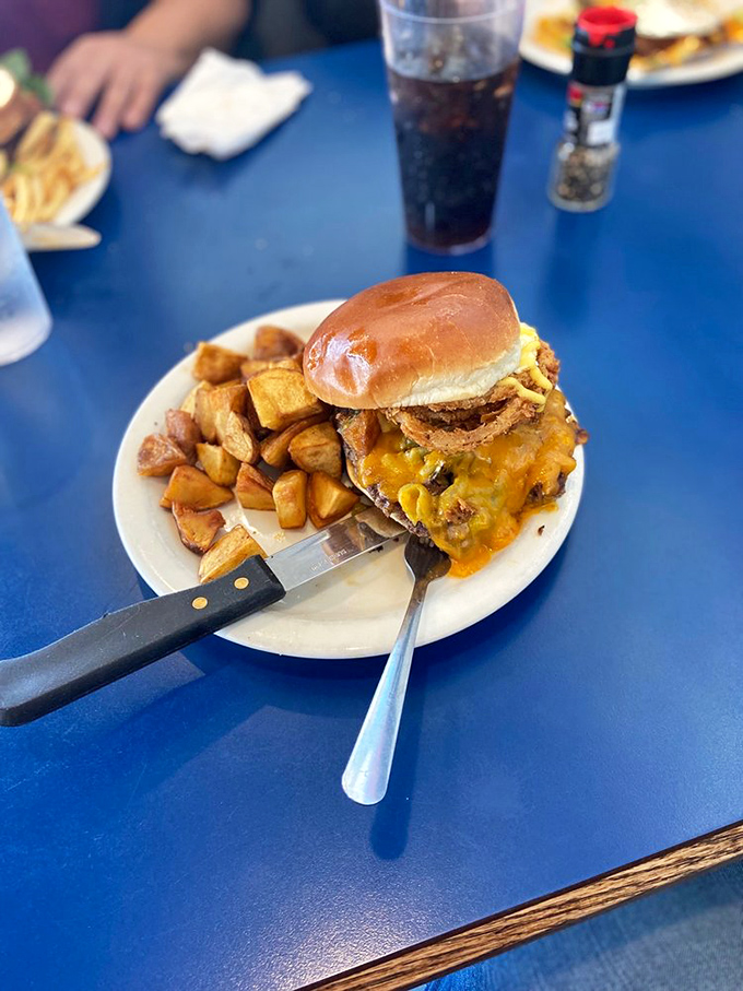A burger that understands the assignment—melty cheese, crispy potatoes, and a knife that signals "you'll need reinforcements for this mission."