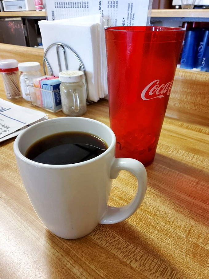 The coffee comes in mugs designed for people who mean business about their caffeine. That red Coca-Cola glass is just waiting for its moment.